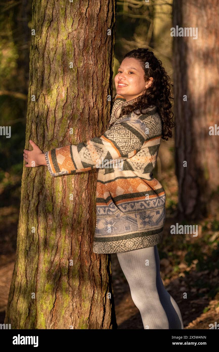 Young woman hugging tree in forest Stock Photo - Alamy