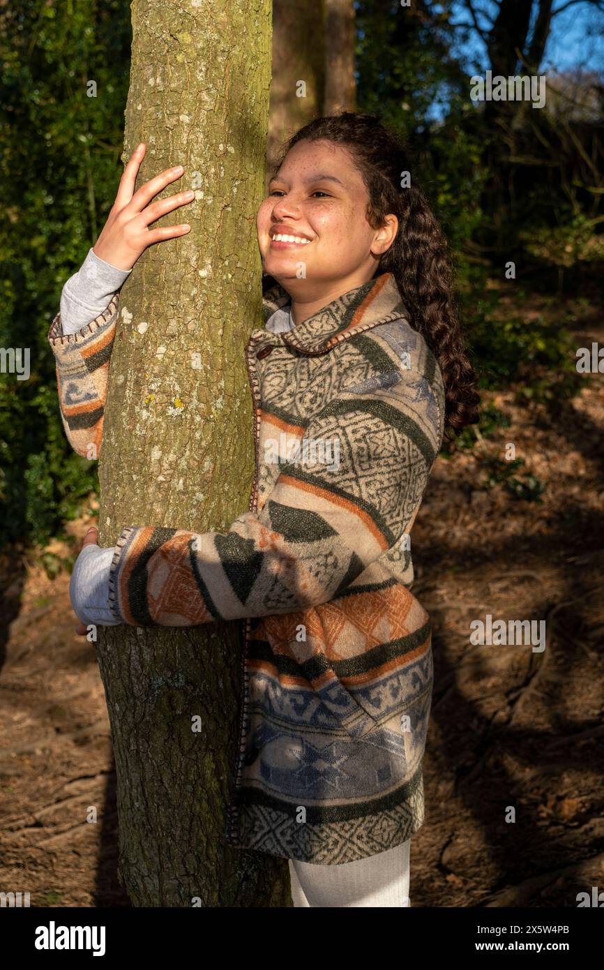 Smiling young woman hugging tree Stock Photo - Alamy