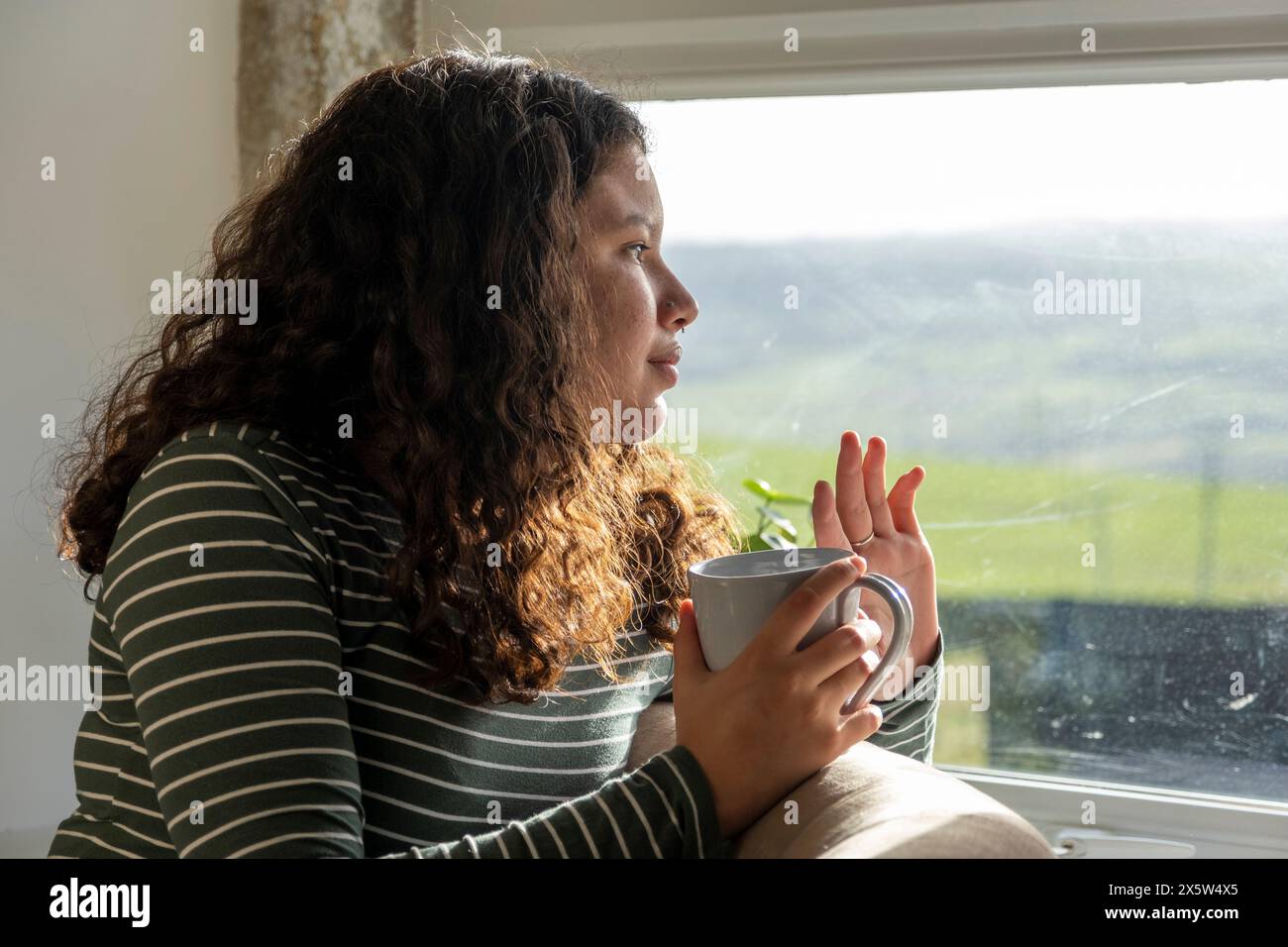 Young woman waving through window Stock Photo - Alamy