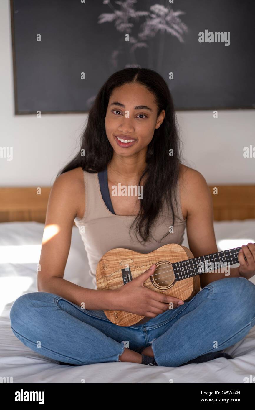 Portrait of young woman playing ukulele Stock Photo - Alamy