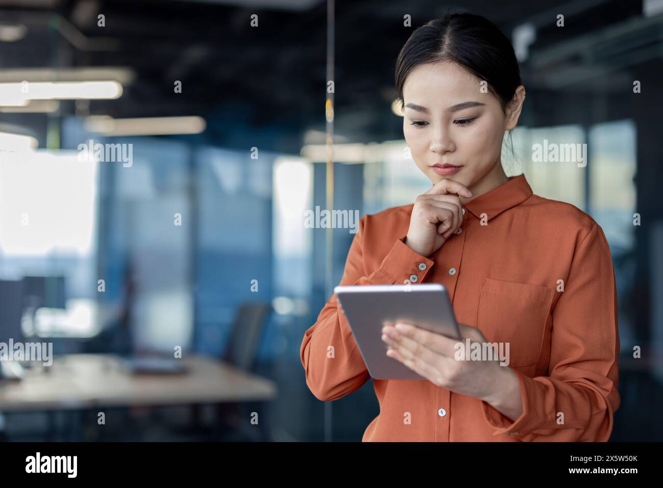 A focused Asian businesswoman with a serious expression is thinking ...