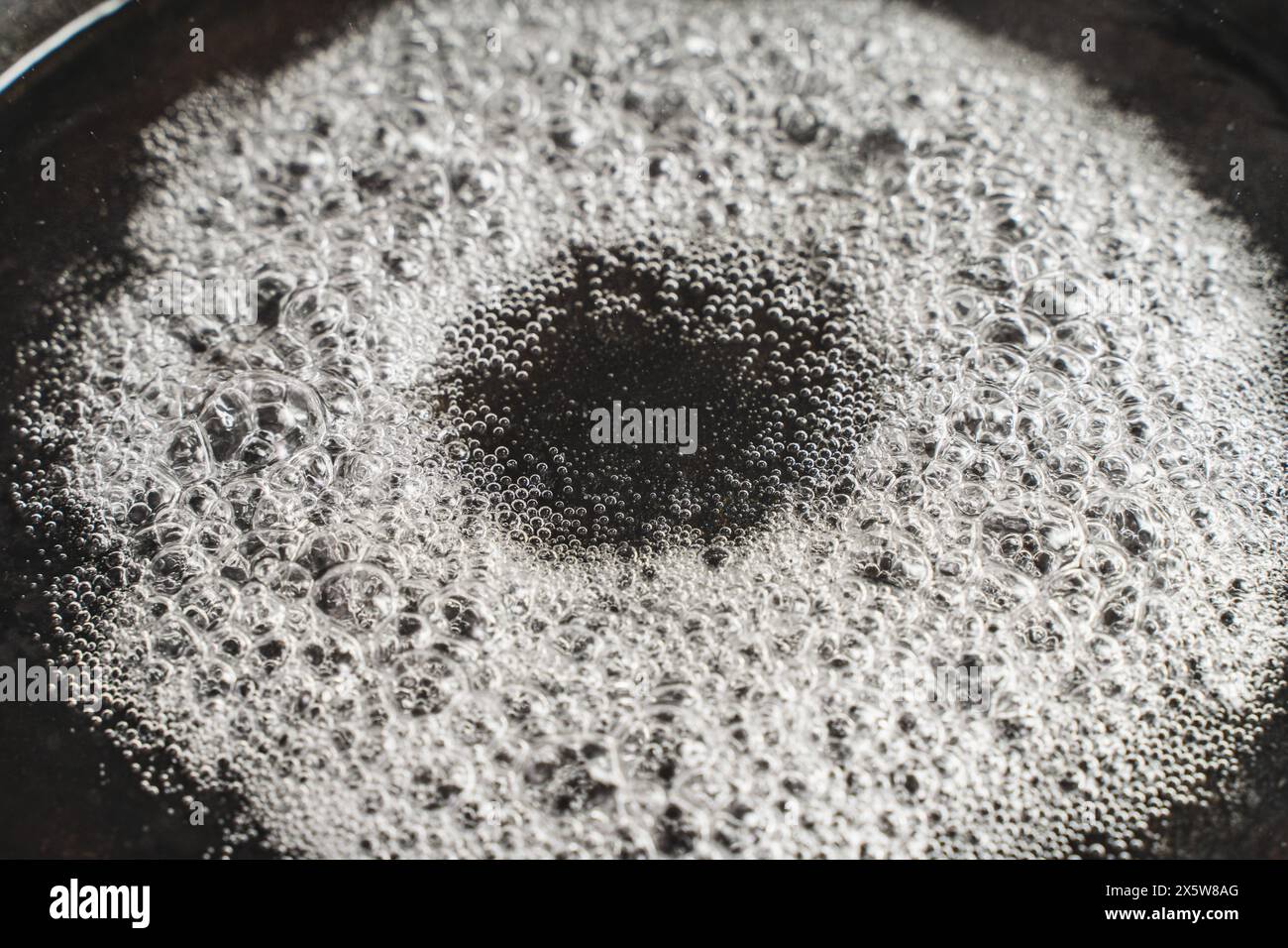 The water bubbles, boiling in a black pan. Background. Boiling butter ...