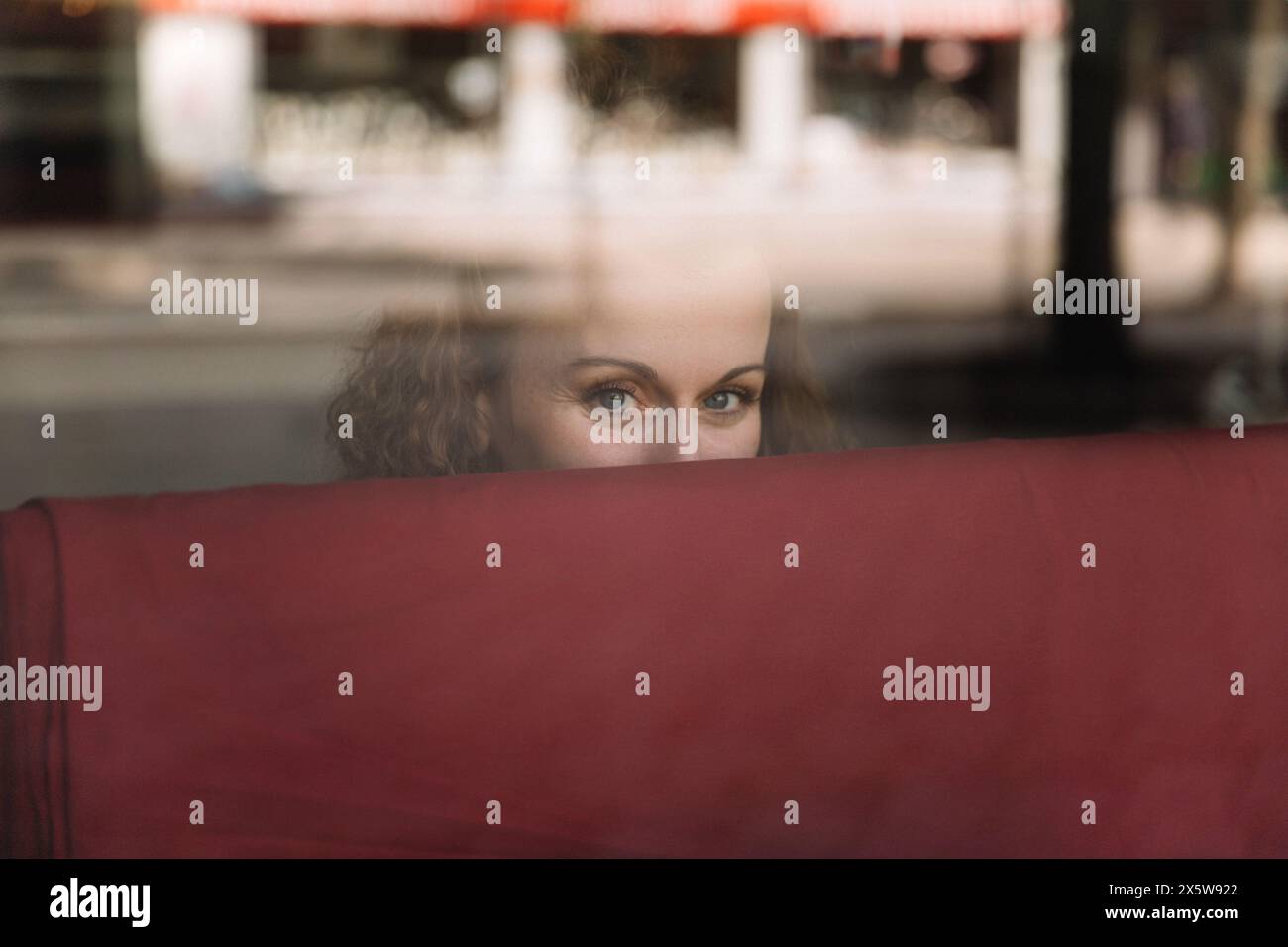 Thoughtful Woman Gazing Out from Behind a Reflective Glass Window in a ...