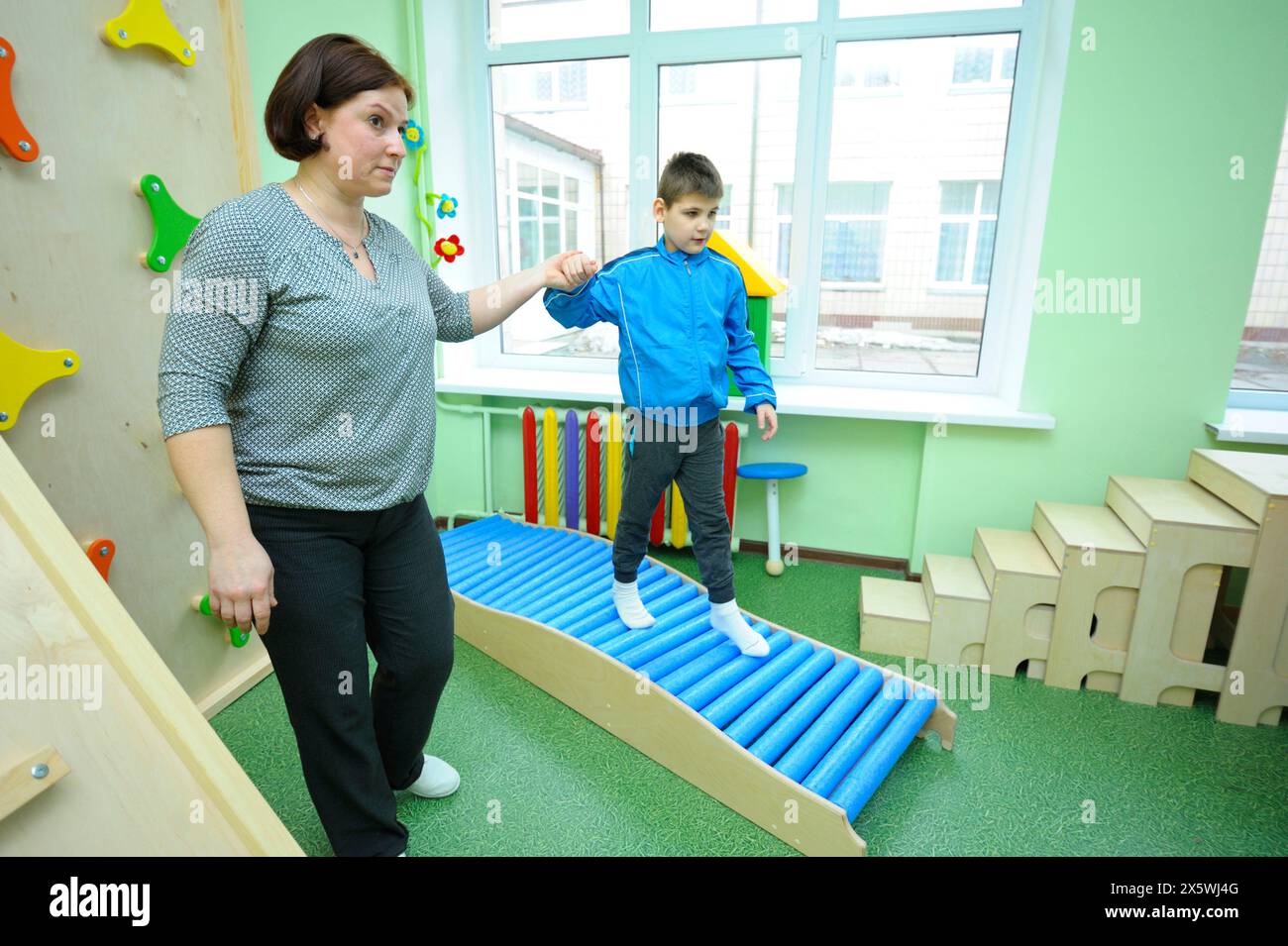 Female therapist helping Down syndrome boy to do exercises at the ...