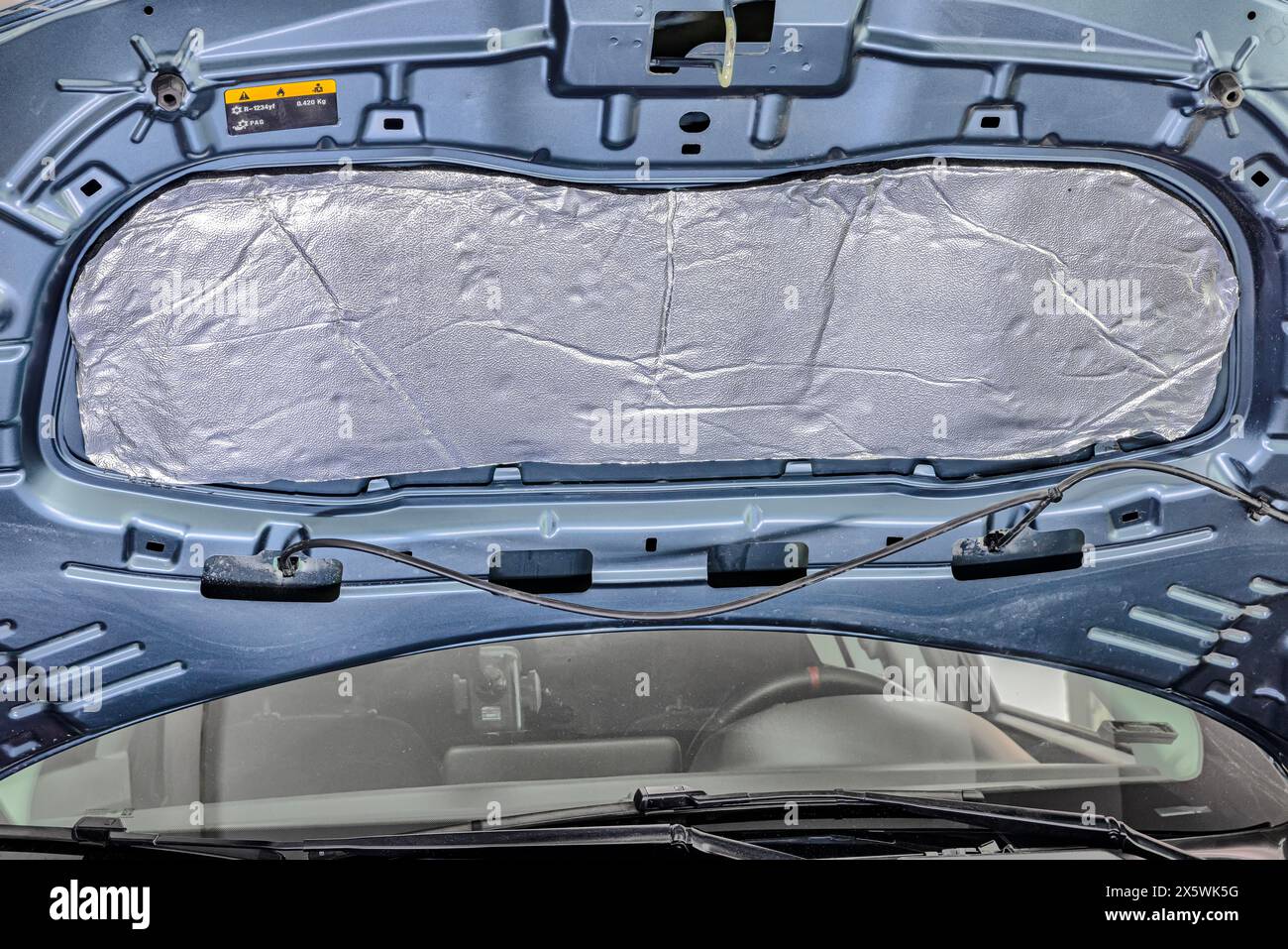 Auto service worker applies soundproof bitumen material to the hood of ...