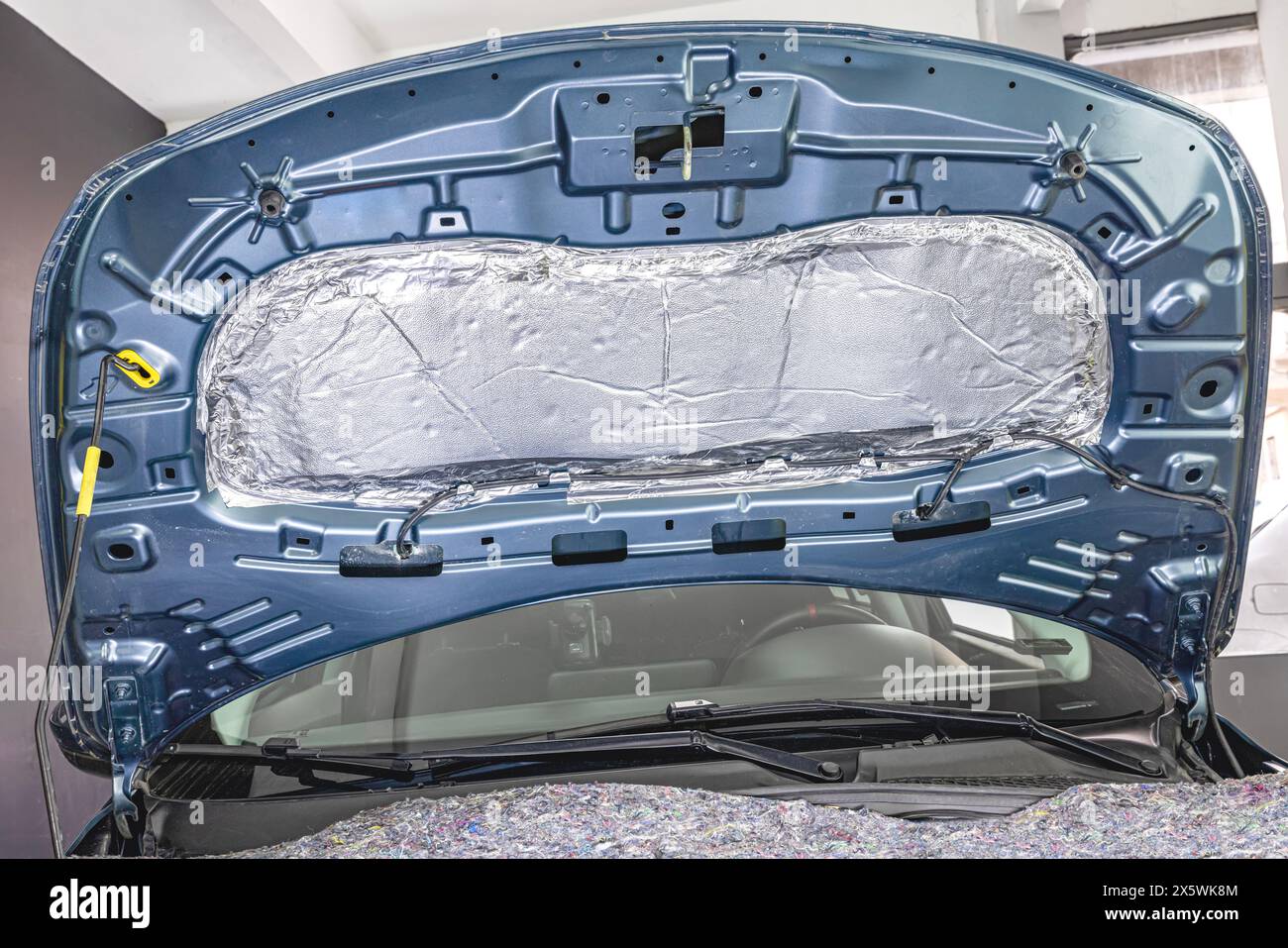 Auto service worker applies soundproof bitumen material to the hood of ...