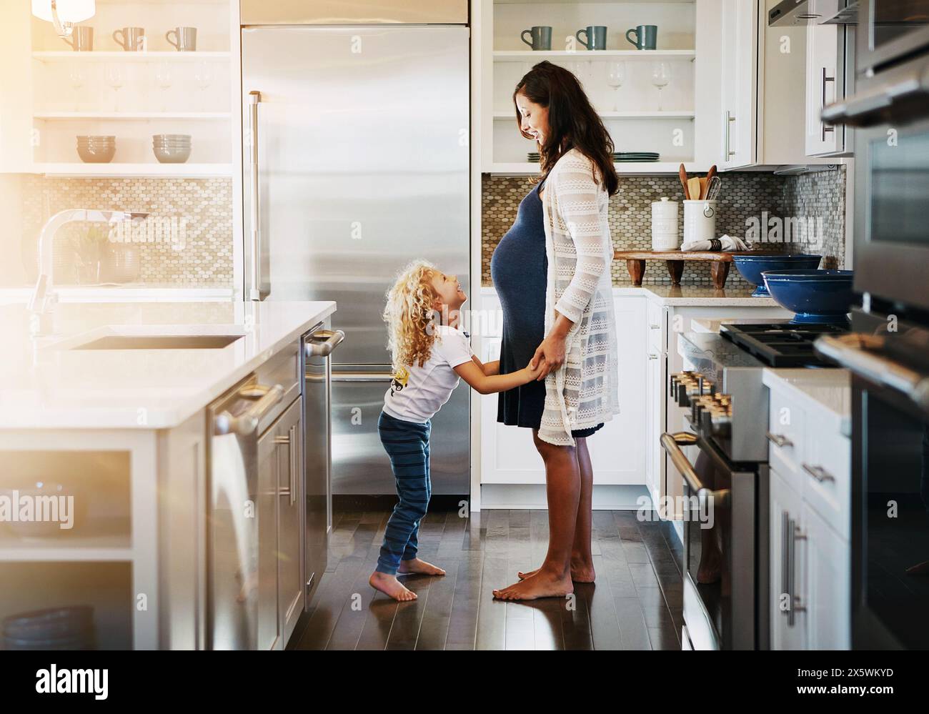 Dancing, music and pregnant mother with child in kitchen listening to ...