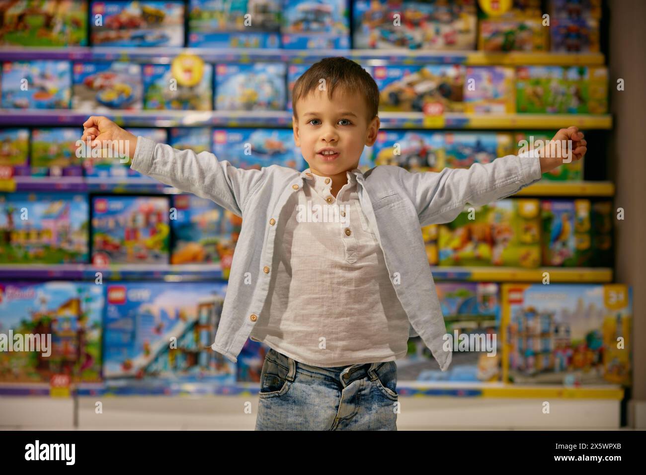 Delighted little boy child standing with toys showcases behind back ...