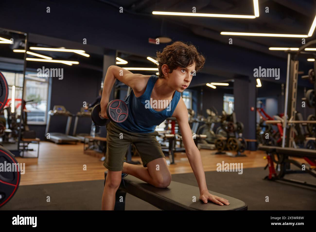 Sportive preteen boy exercising with heavy dumbbells at gym Stock Photo ...