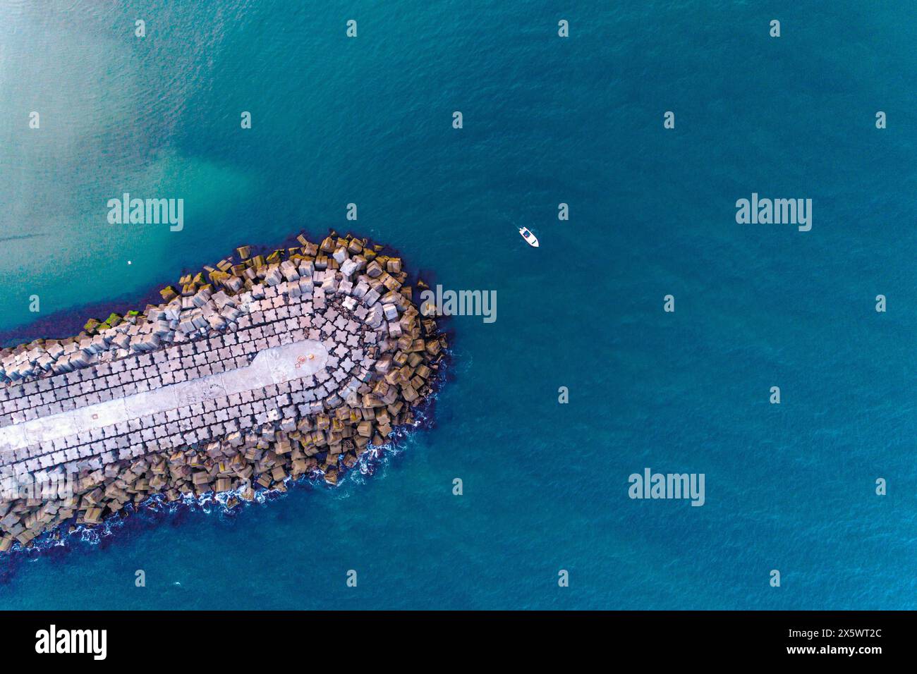 small boat next to a breakwater built with concrete blocks. Overhead ...