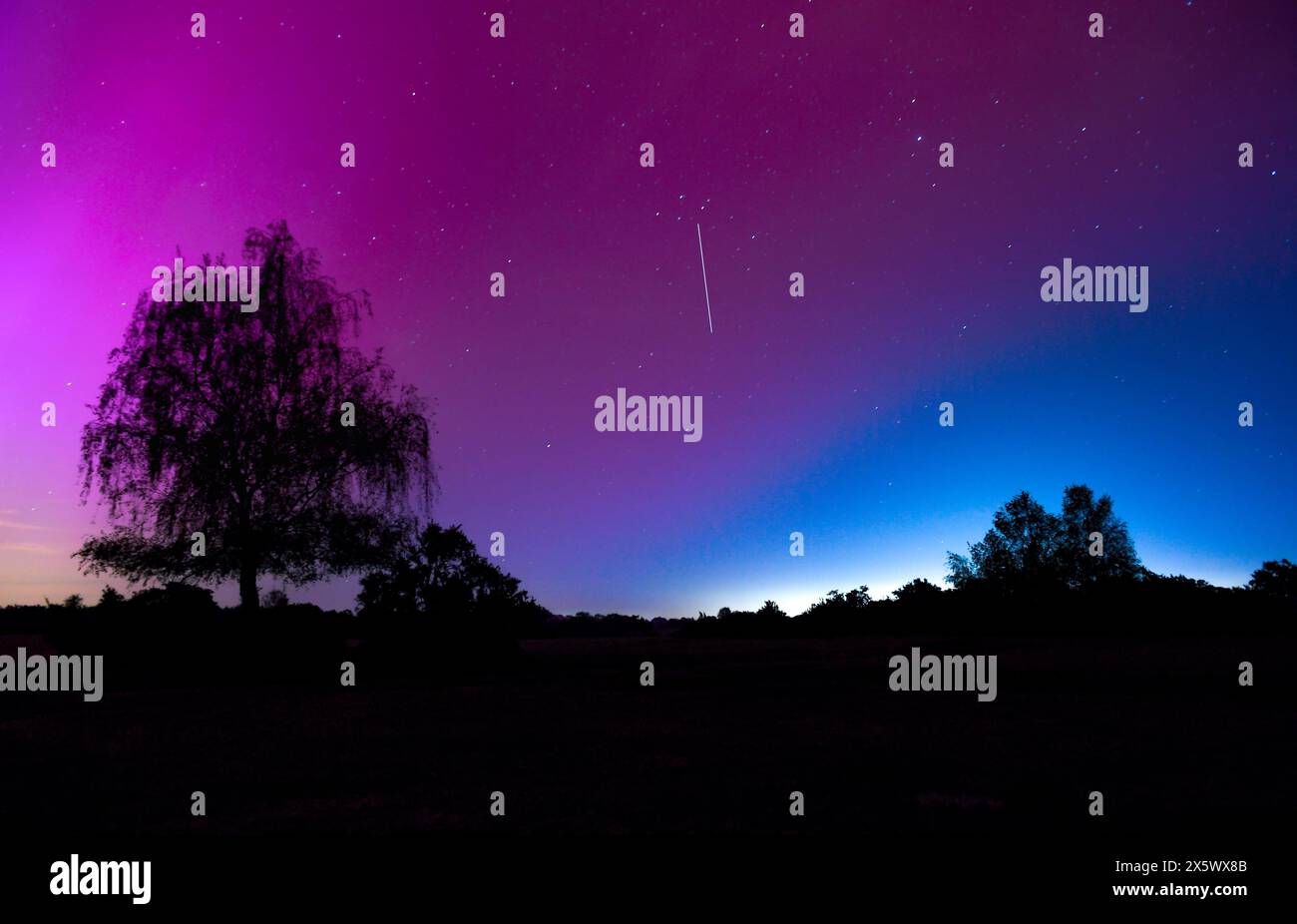 A satellite crosses the sky during the Northern Lights G5 solar storm ...