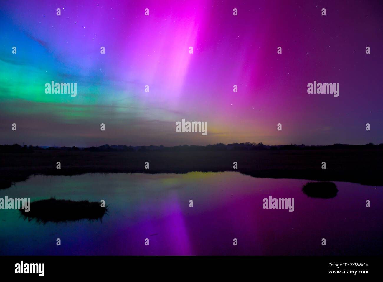 The Northern lights reflecting in a small water hole on Canada Common ...