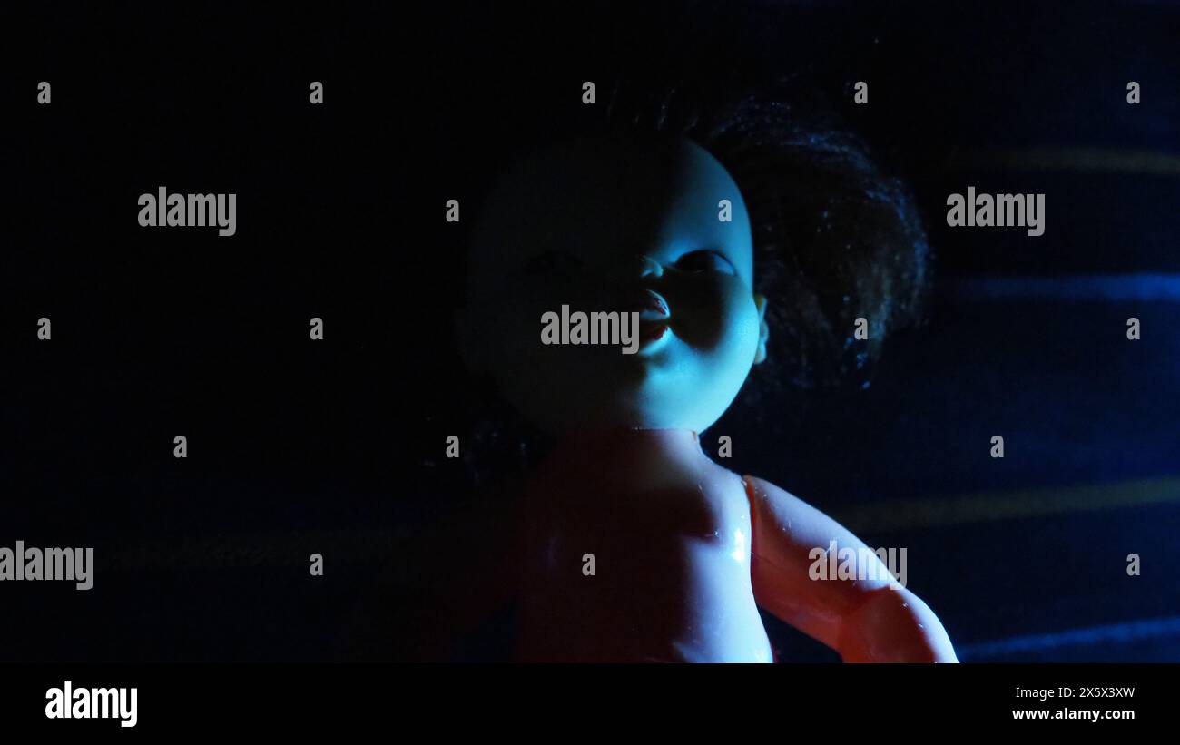 Scary doll in the dark with red and blue lights. The theme of Halloween ...