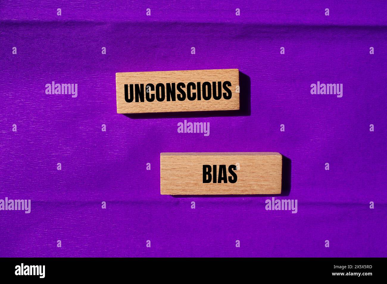 Unconscious bias words written on wooden blocks with purple background. Conceptual unconscious ...