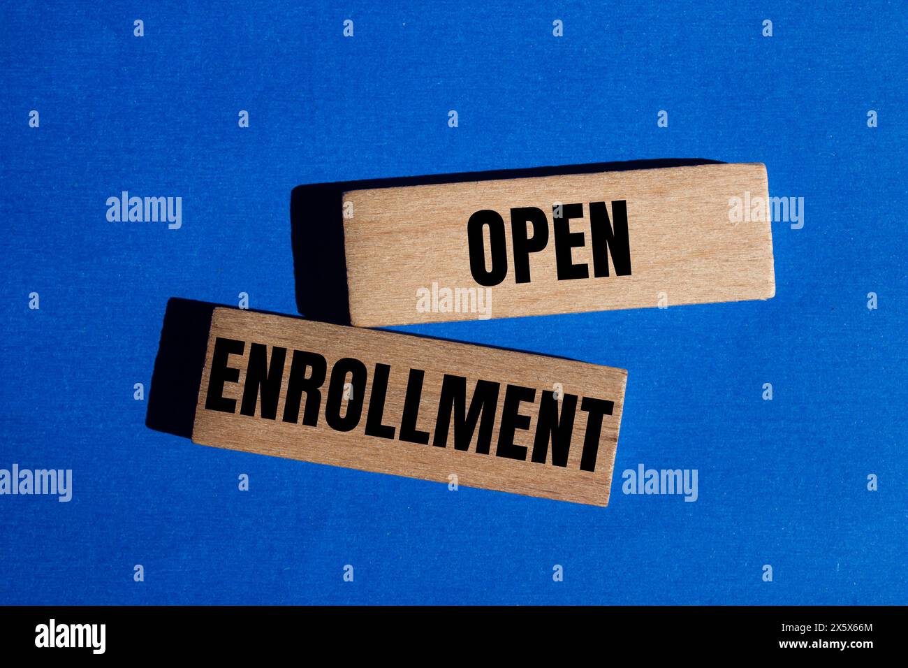 Open enrollment written on wooden blocks with blue background ...