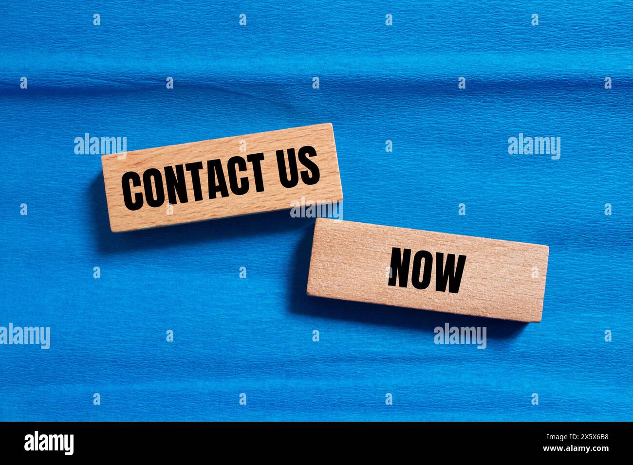 Contact us now words written on wooden blocks with blue background ...