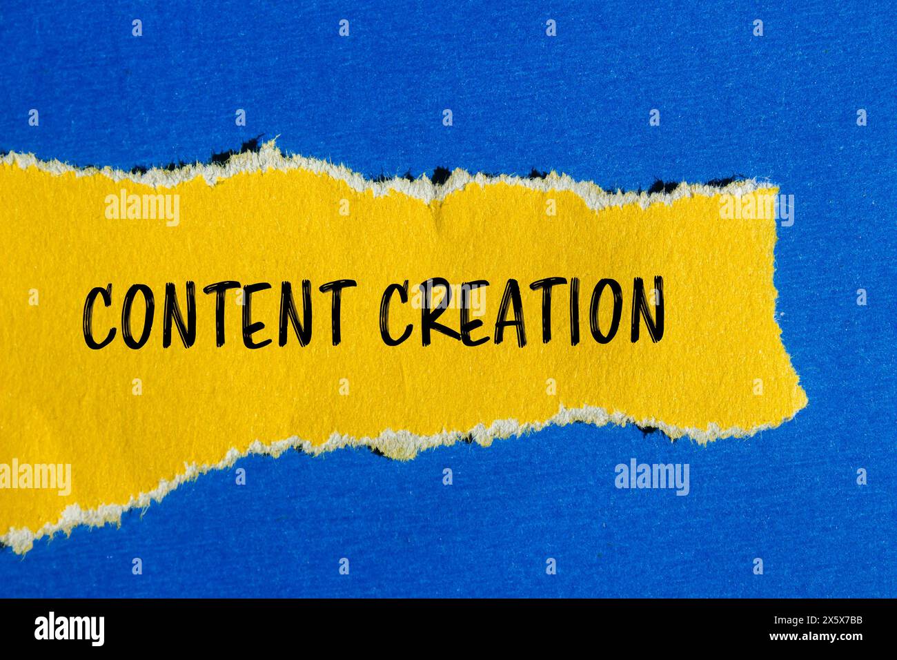 Content creation words written on ripped yellow paper with blue background. Conceptual content ...