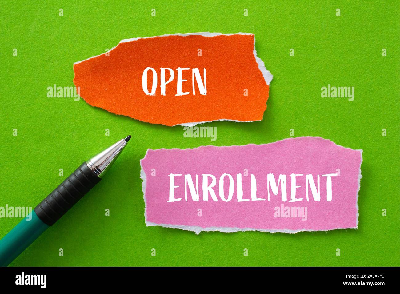 Open enrollment words written on ripped paper pieces with green ...