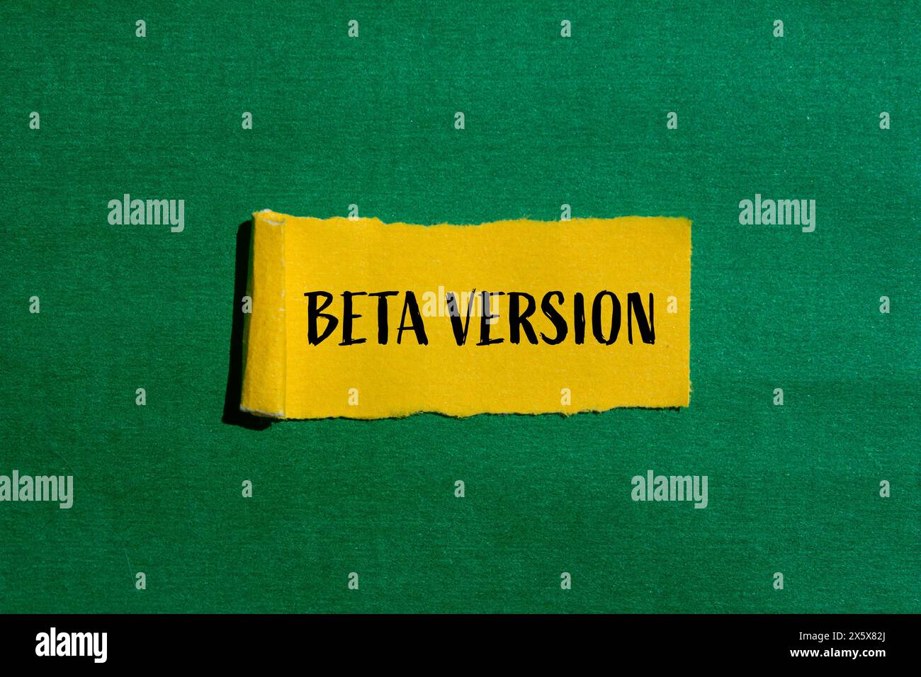Beta version words written on ripped yellow paper with green background ...