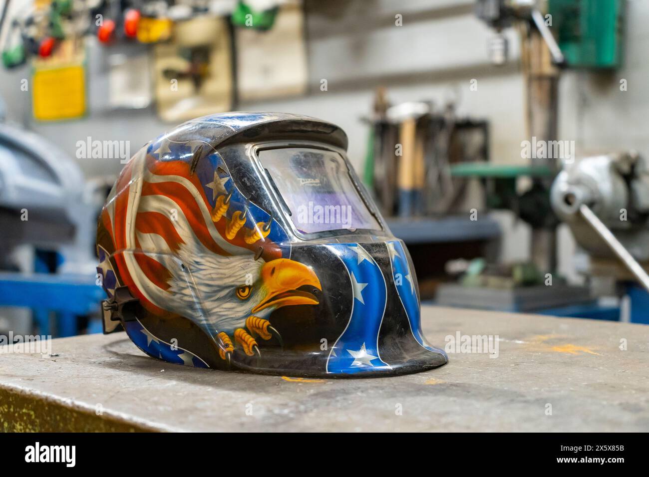 A welding helmet decorated with an American eagle on a table in a ...