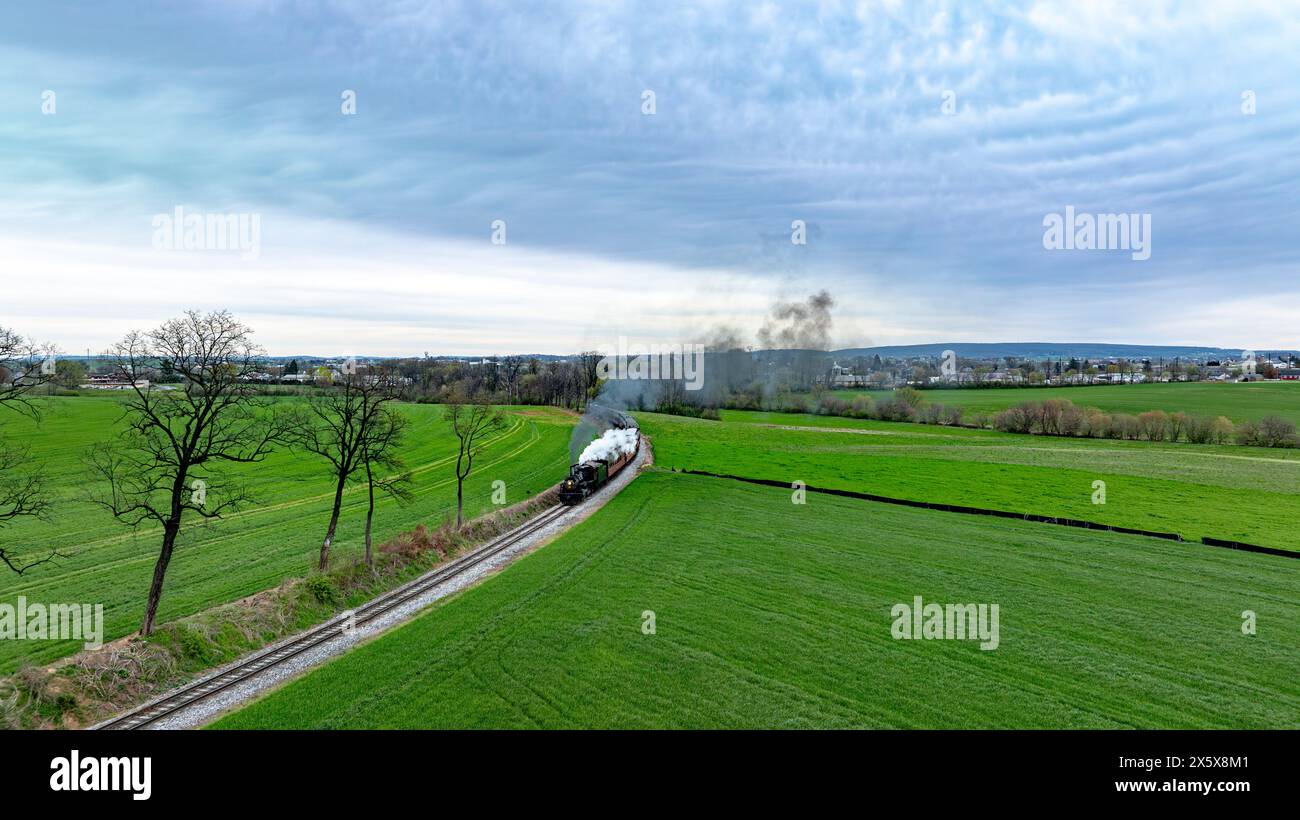 Dramatic aerial capture of a vintage steam train chugging along a curvy ...