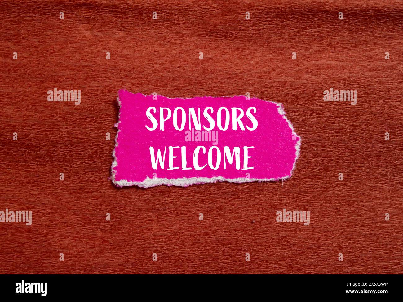 Sponsors welcome words written on ripped pink paper piece with brown ...