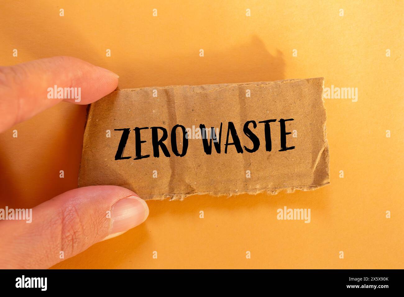 Zero waste written on ripped cardboard paper piece with orange background. Conceptual zero waste ...