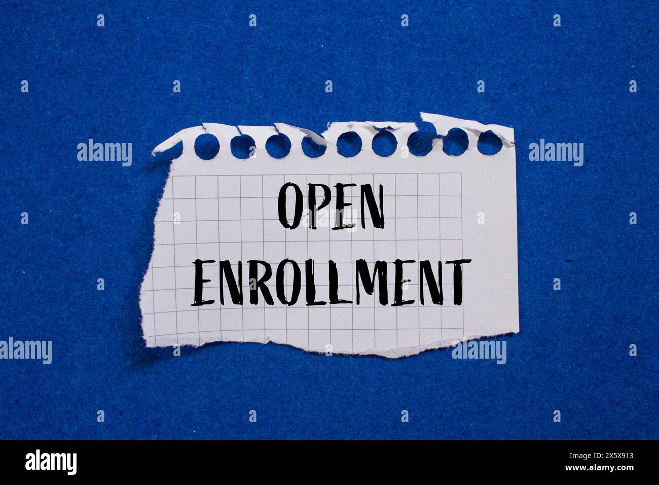 Open enrollment words written on ripped white paper with blue ...