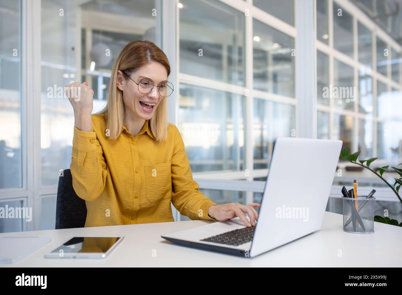 A cheerful young woman in a modern office, showing excitement and ...