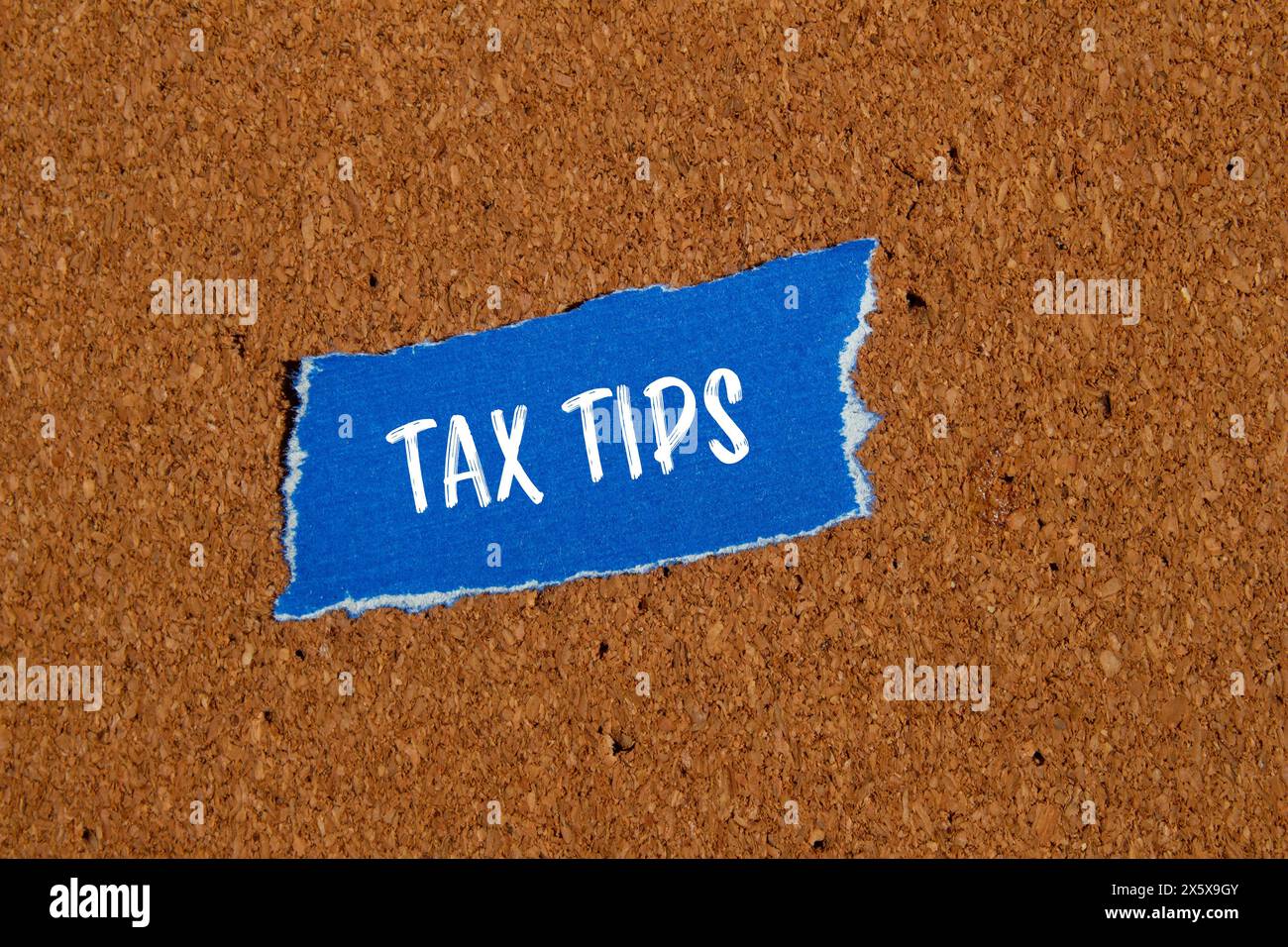 Tax tips words written on ripped blue paper piece with brown background ...