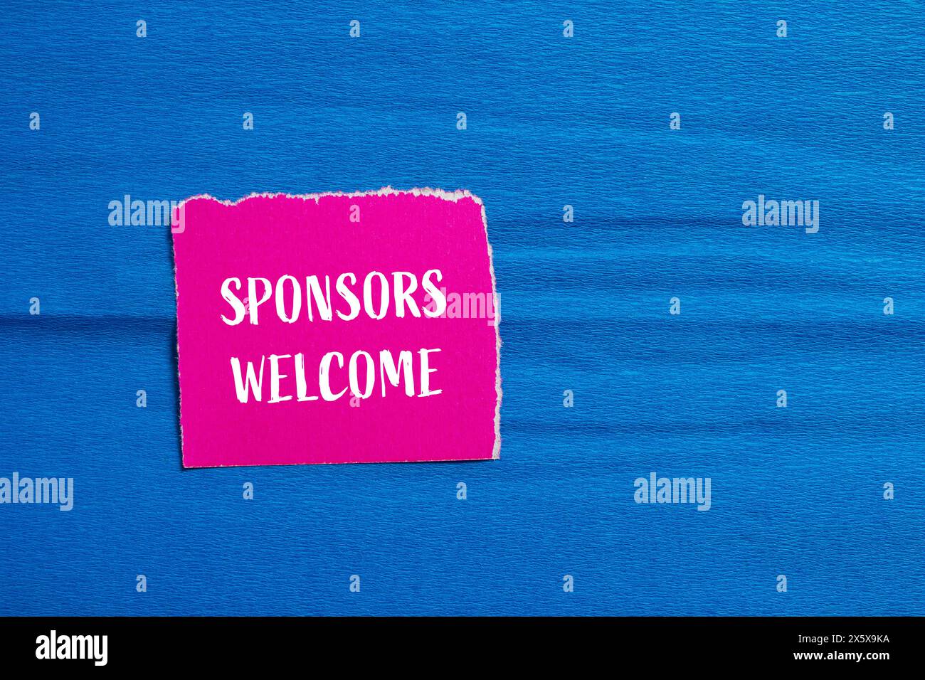 Sponsors welcome words written on ripped pink paper piece with blue ...