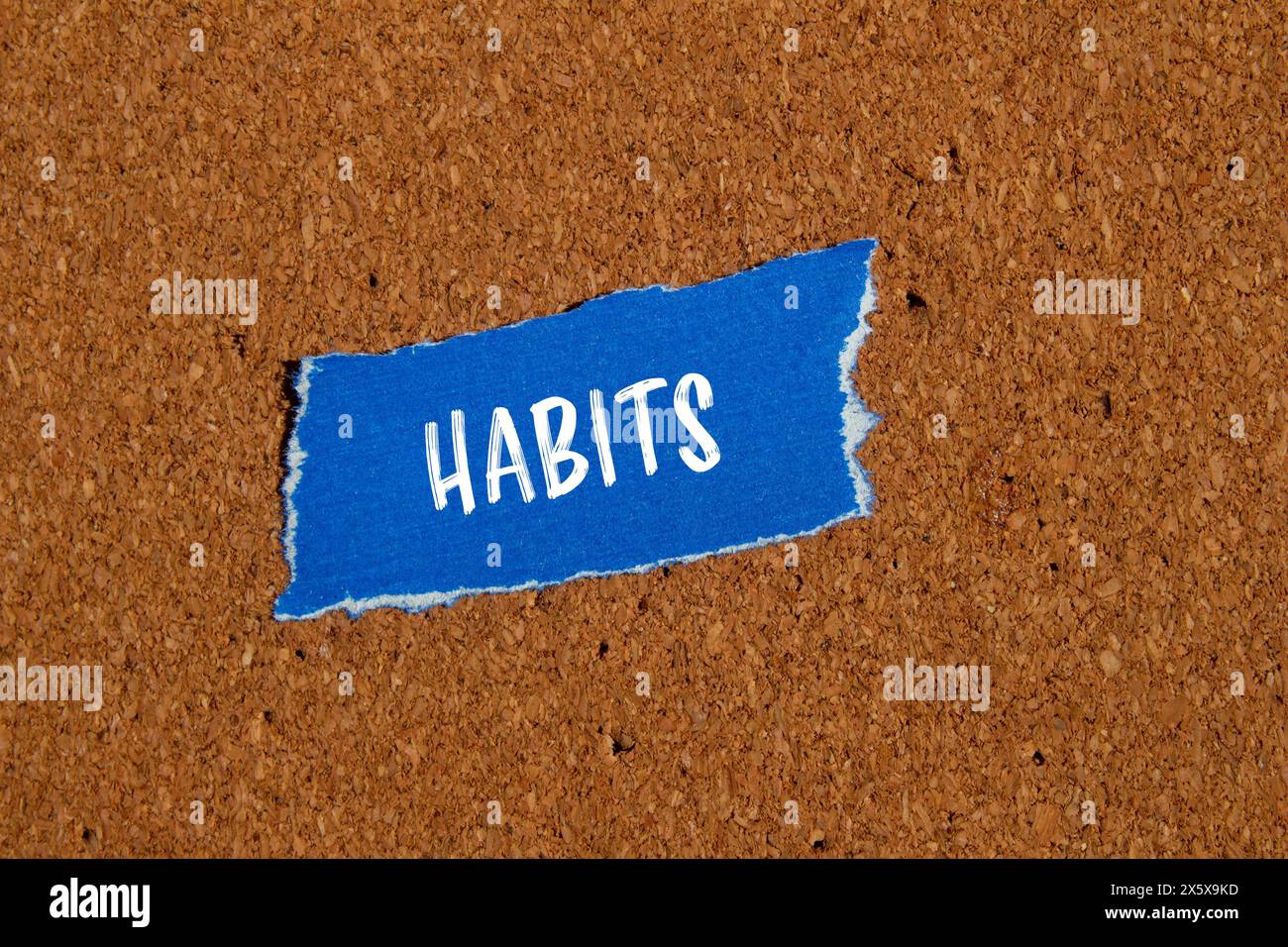 Habits word written on ripped blue paper piece with brown background ...