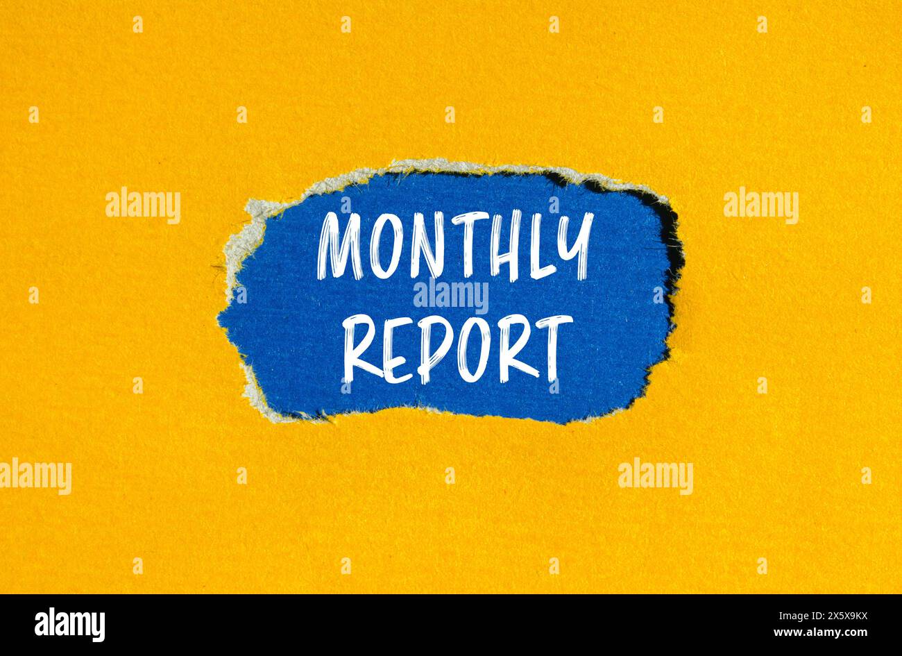 Monthly report words written on ripped yellow paper with blue ...