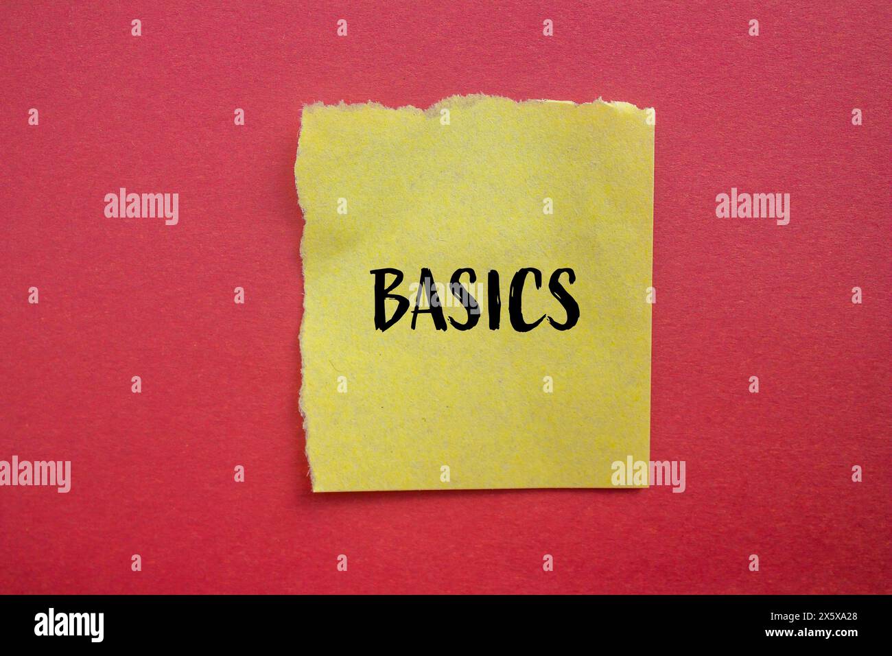 Basics word written on ripped yellow paper piece with red background ...