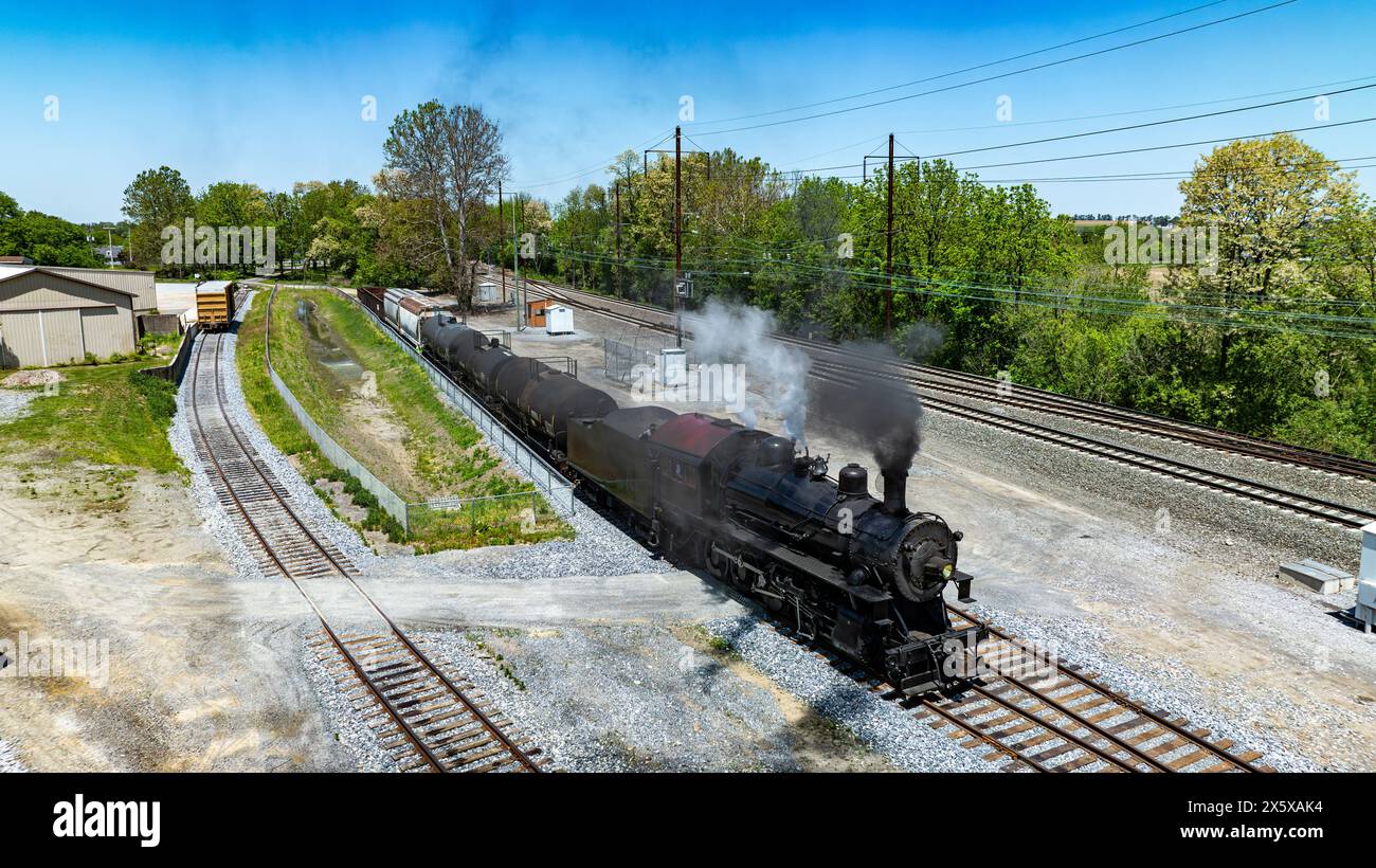 An aerial powerful vintage steam train moves through an industrial rail ...