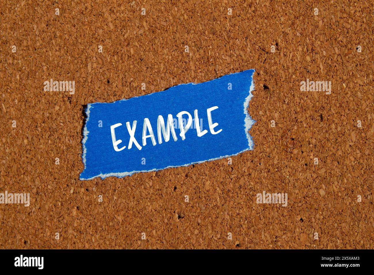 Example word written on ripped blue paper piece with brown background ...