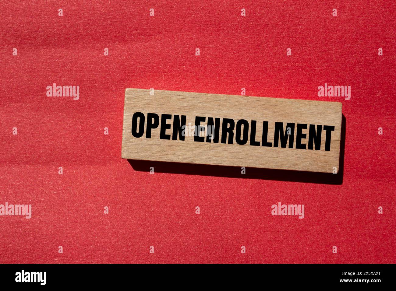 Open enrollment words written on wooden block with red background ...