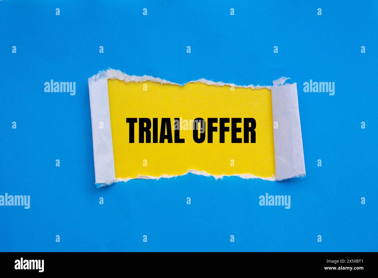 Trial offer words written on ripped blue paper with yellow background ...