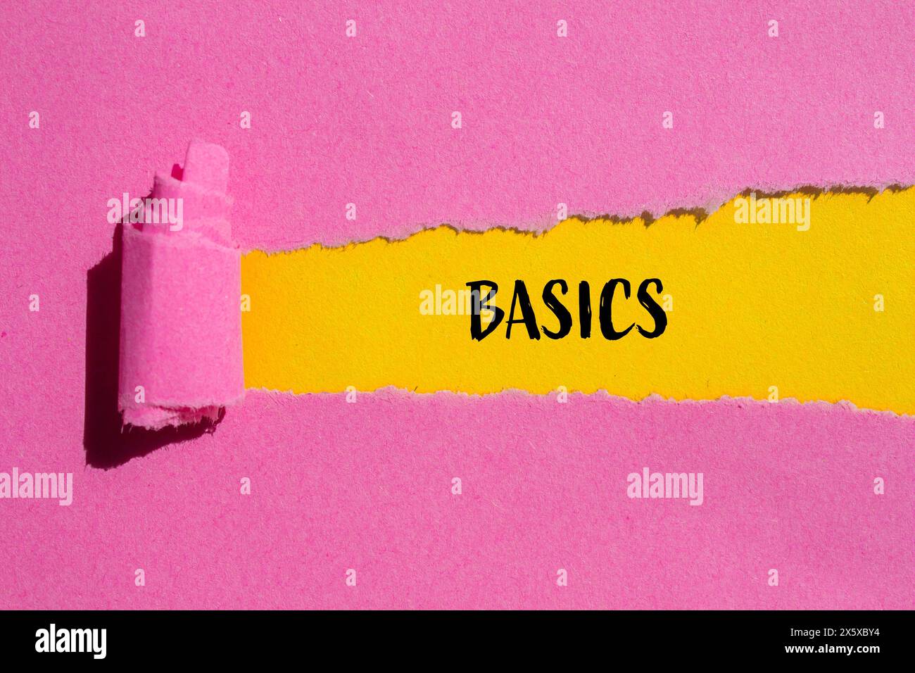Basics word written on ripped pink paper with yellow background ...