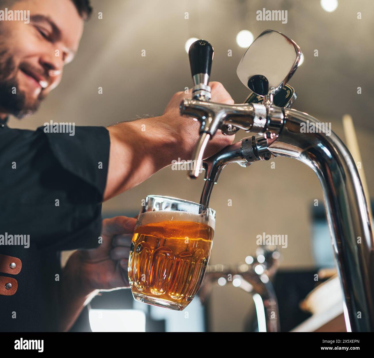 Smiling stylish bearded barman dressed black uniform with an apron ...