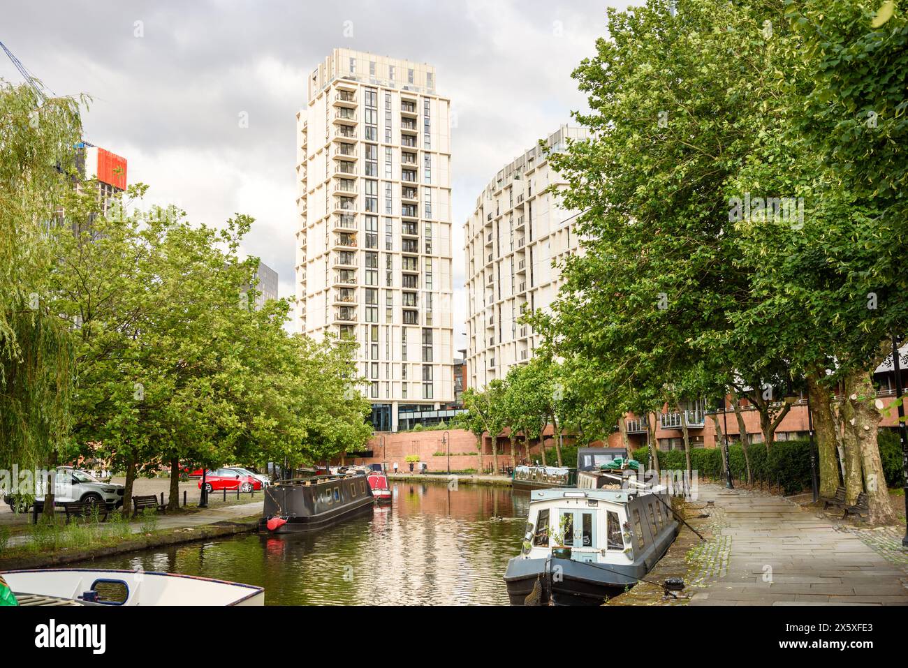 Modern apartment buildings along a canal lined with stone paths and ...