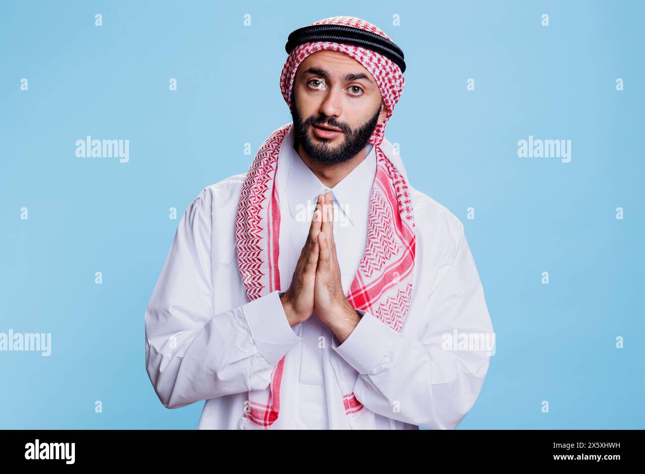 Man wearing traditional muslim thobe and ghutra clothes praying studio ...