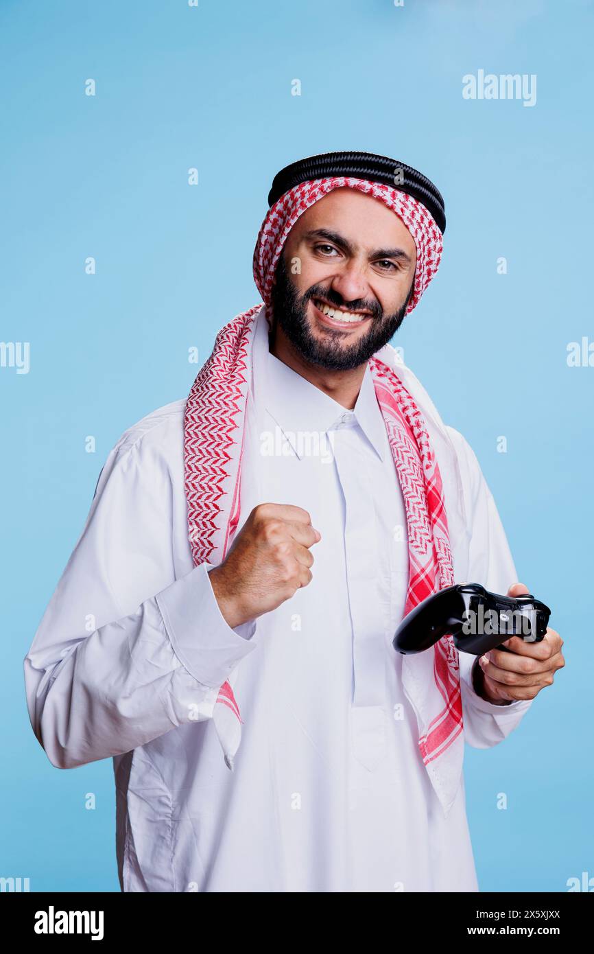 Happy muslim man showing winner gesture with clenched fist and holding ...