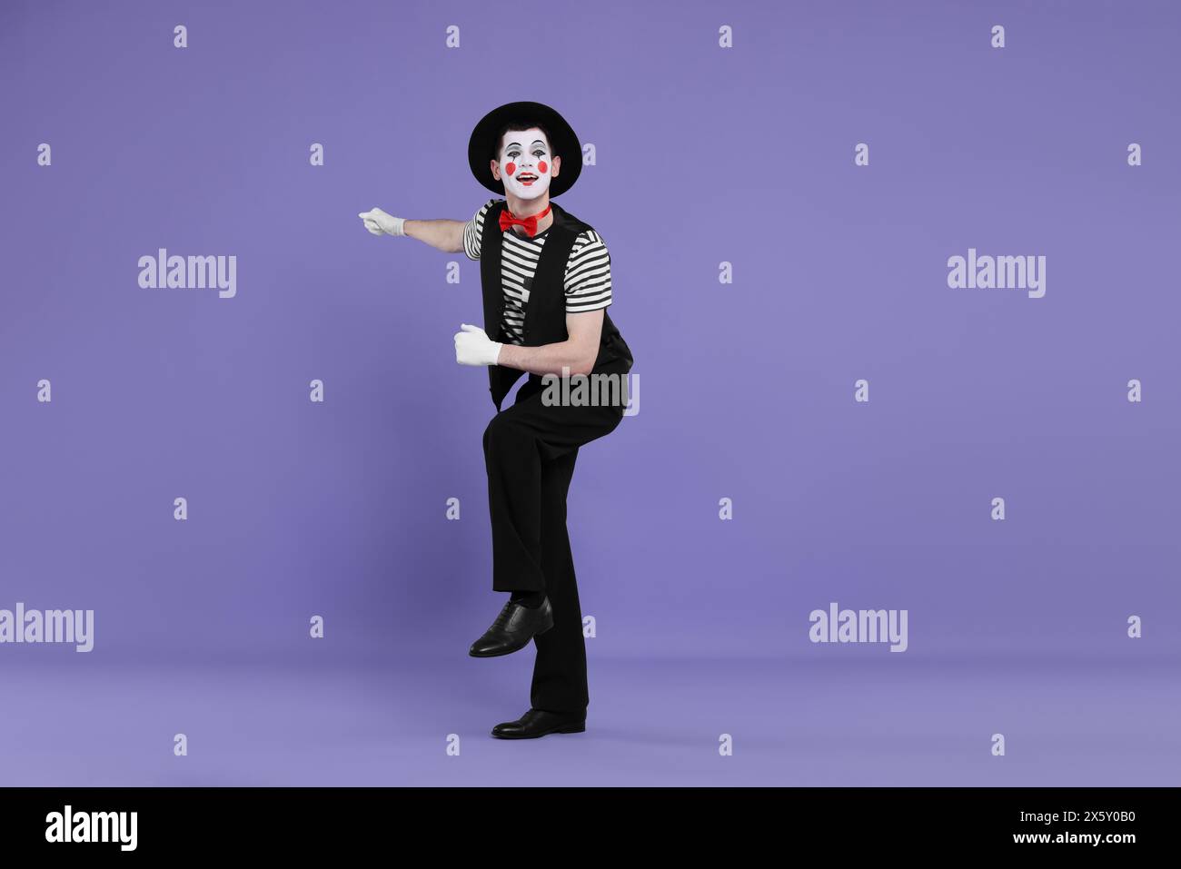 Funny mime artist in hat posing on purple background Stock Photo - Alamy