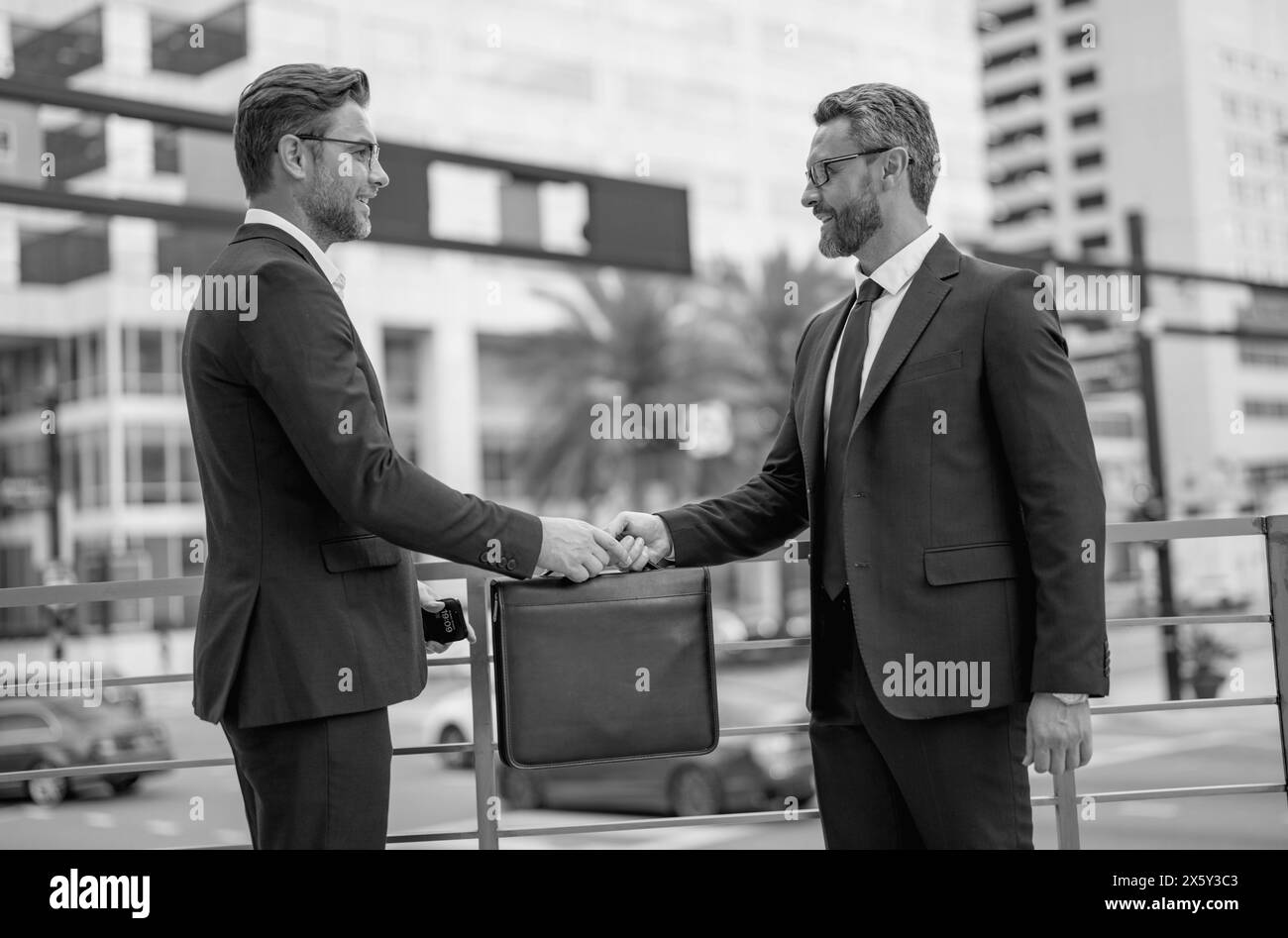 Men in suits handover briefcase outdoor. Business deal. Two business ...