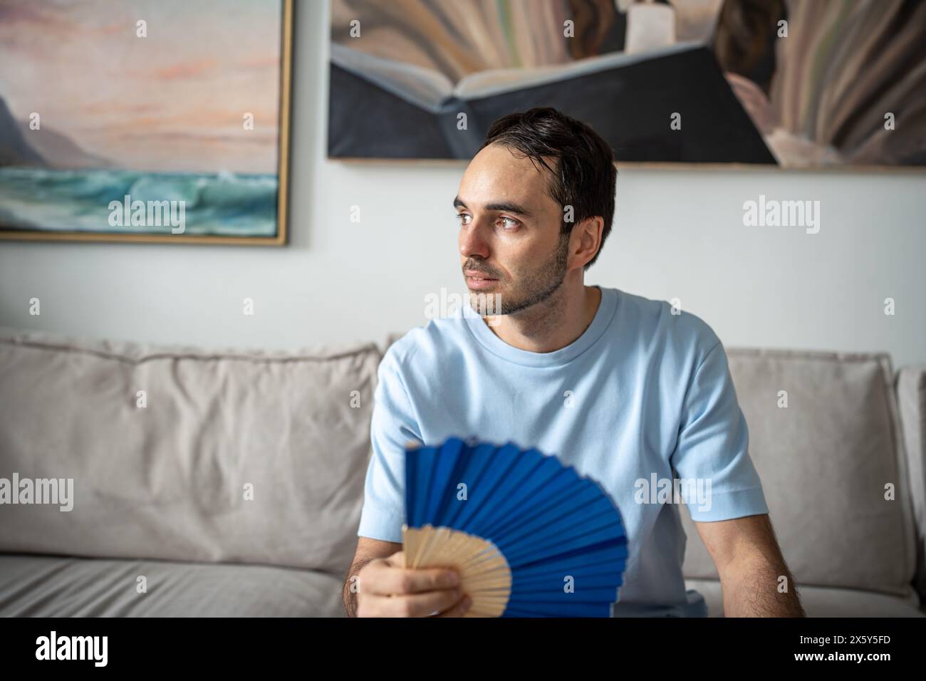 Man blowing with fan, coping with heat. Guy experiencing discomfort ...