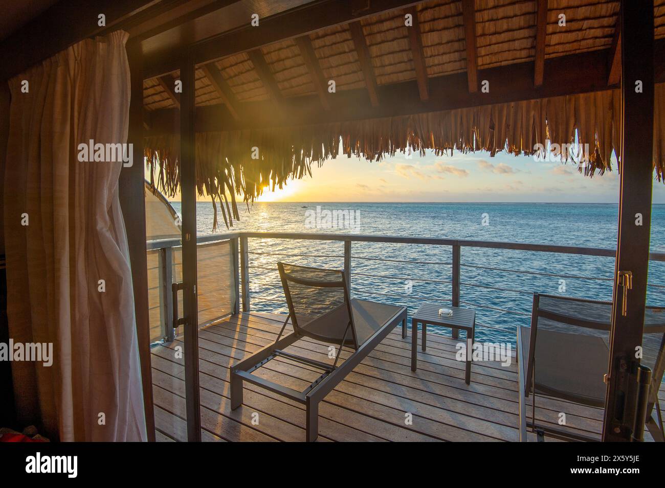 View over sunset from the deck of a bungalow on stilts, Manava Beach ...