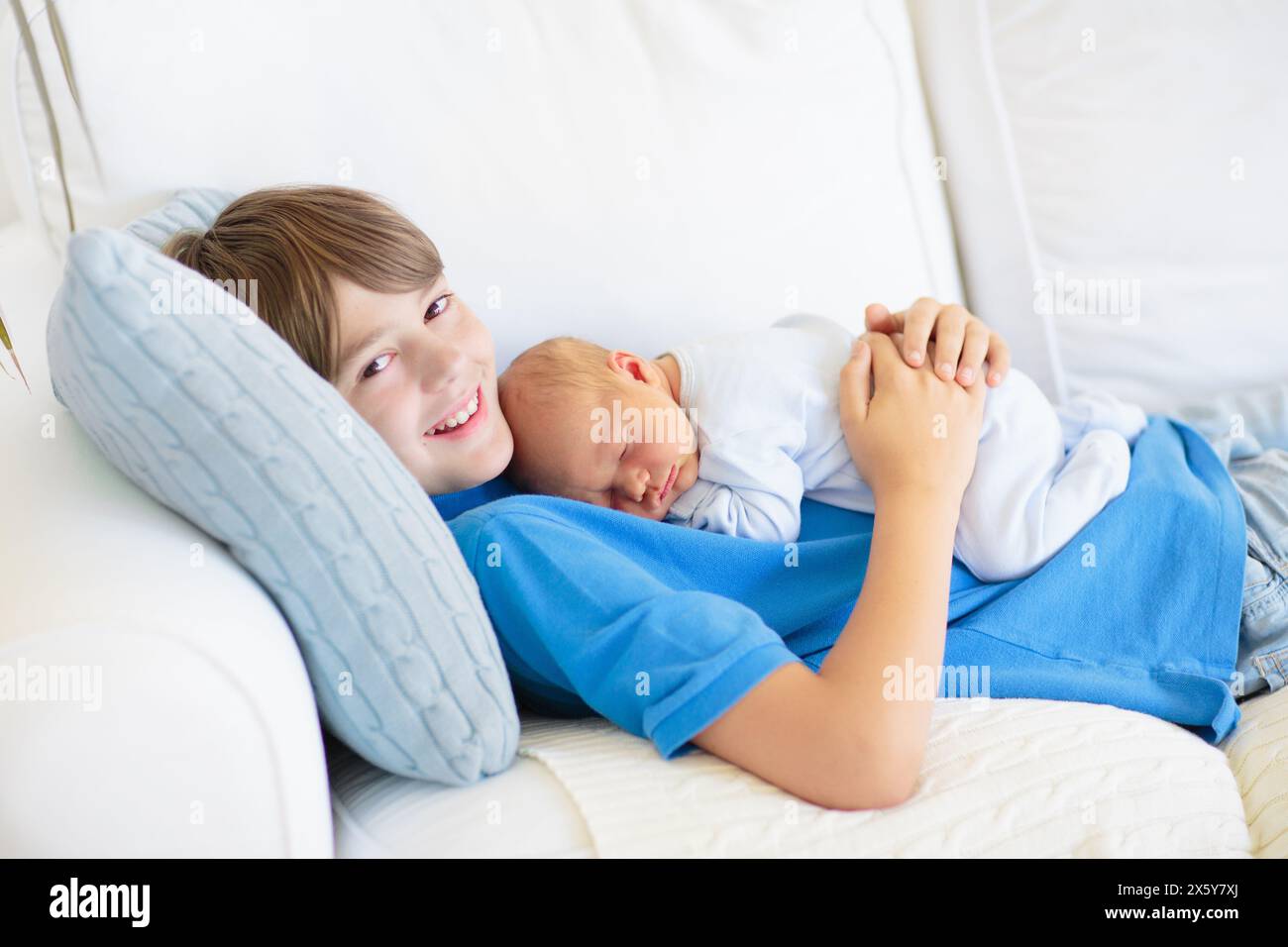 Happy laughing boy holding his sleeping newborn baby brother. Siblings ...