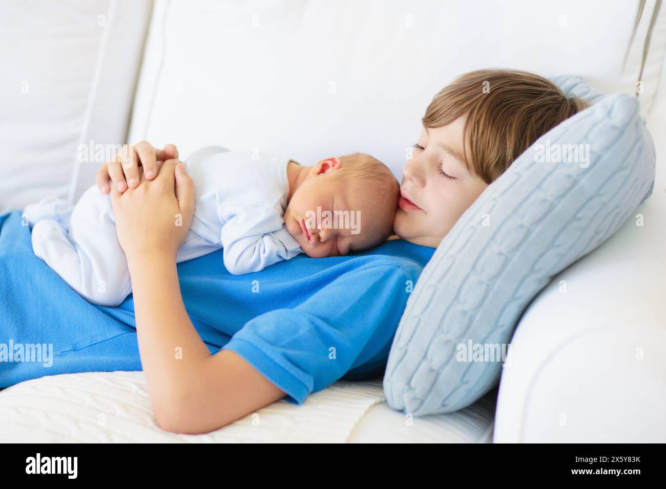 Happy laughing boy holding his sleeping newborn baby brother. Siblings ...