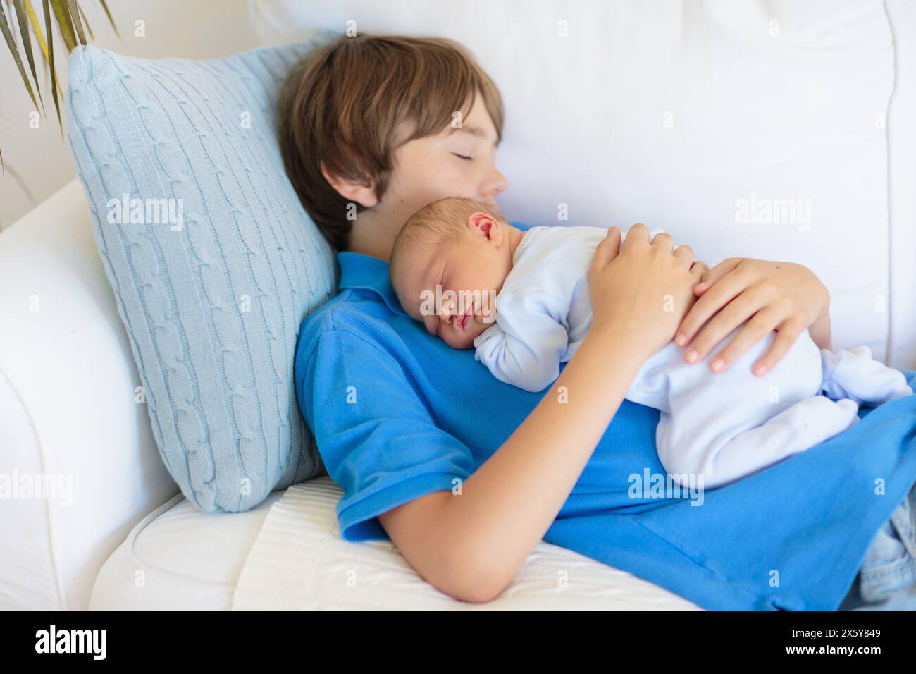 Happy laughing boy holding his sleeping newborn baby brother. Siblings ...